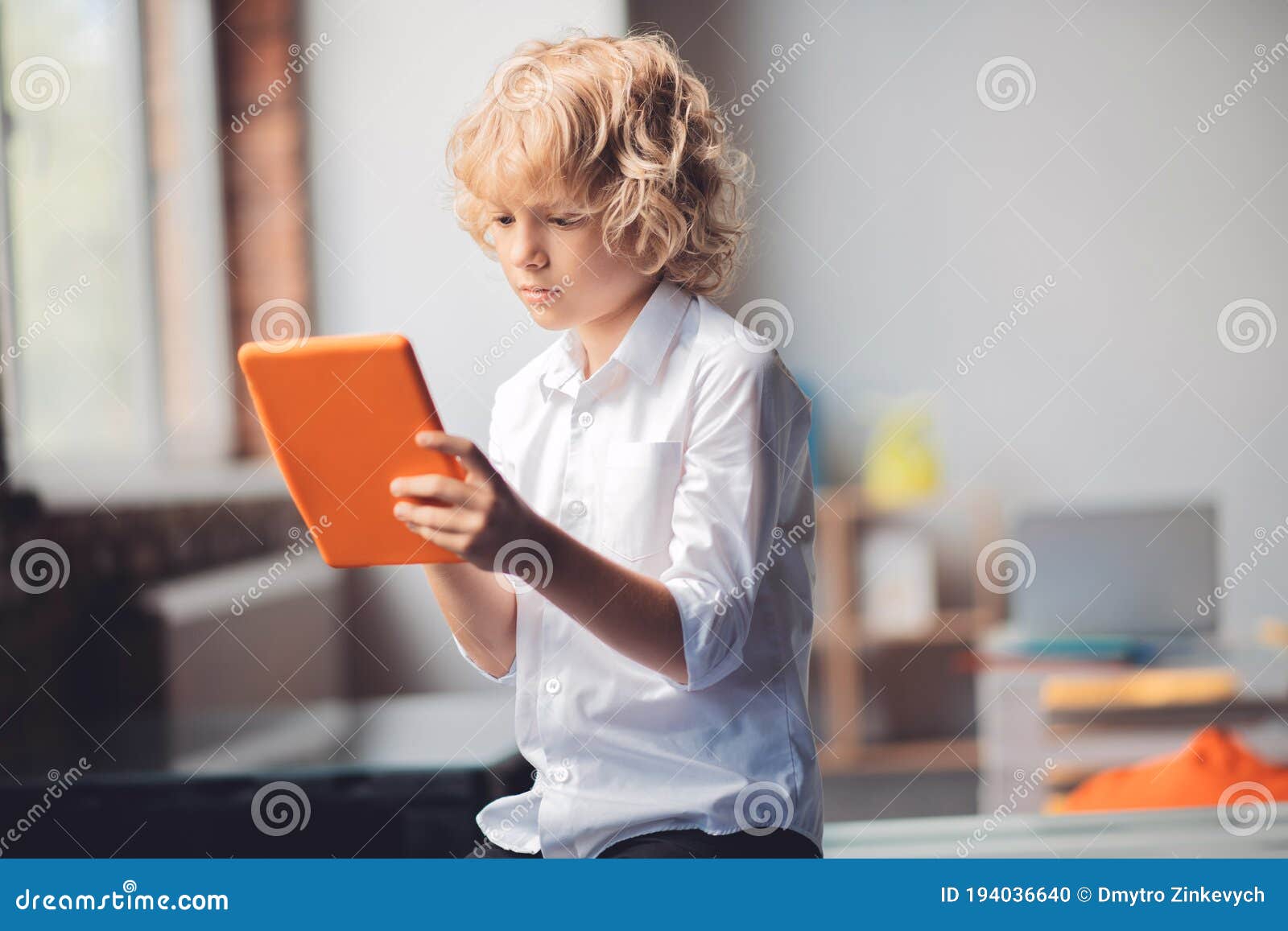 Cute Blonde Boy Holding His Tablet and Typing a Message Stock Photo ...