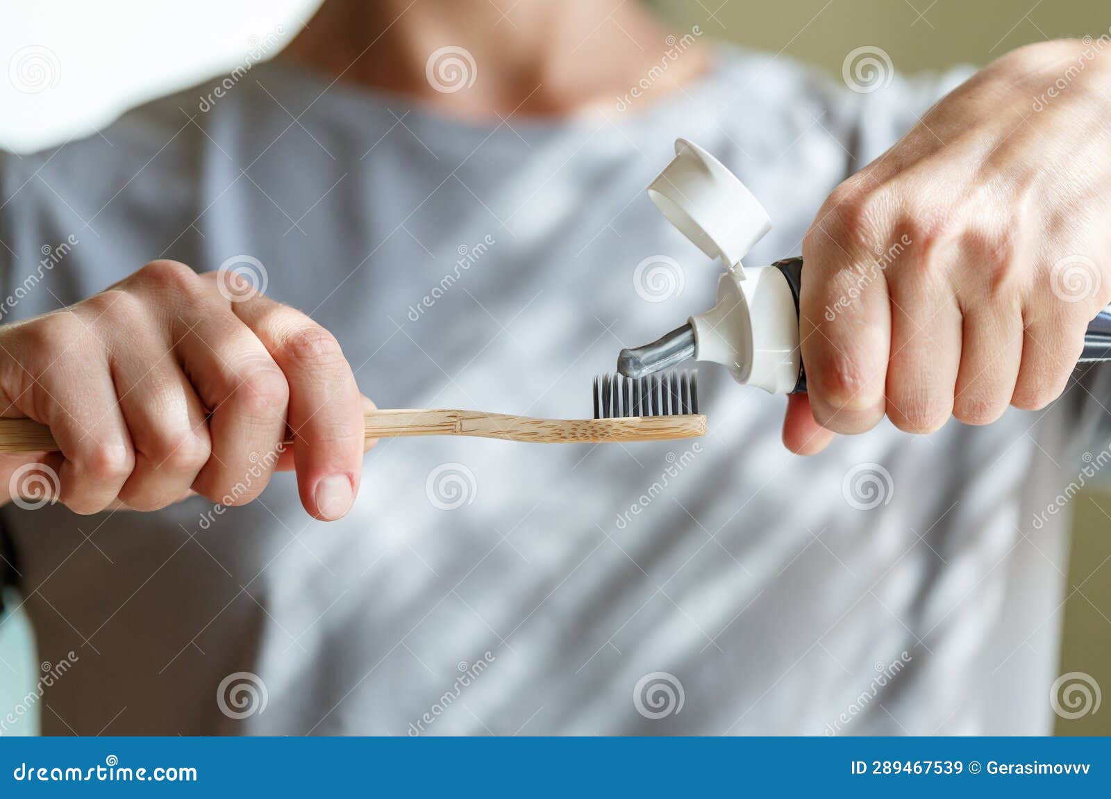 Applying Toothpaste on a Bamboo Tooth Brush. Hands Squeezing Tube with ...