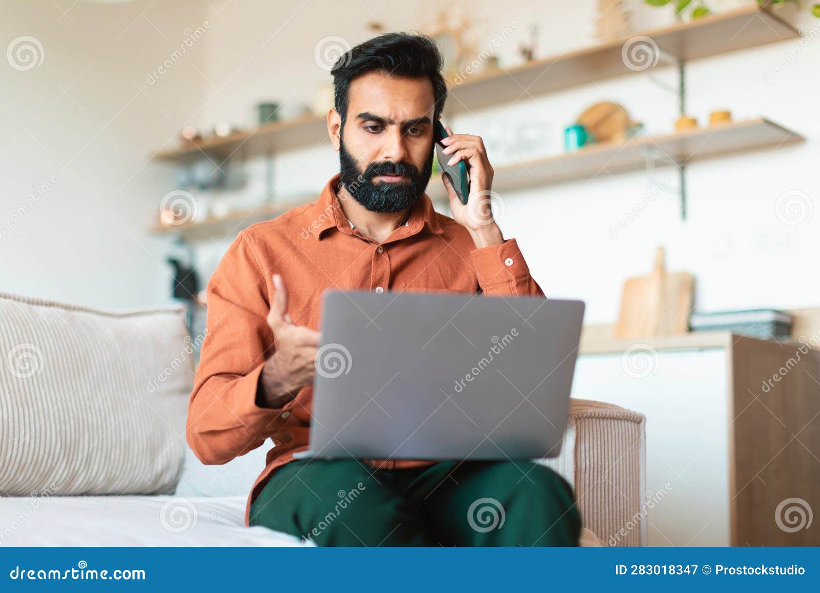 Arab Man Talking on Phone Using Laptop Expressing Discontent Indoor ...