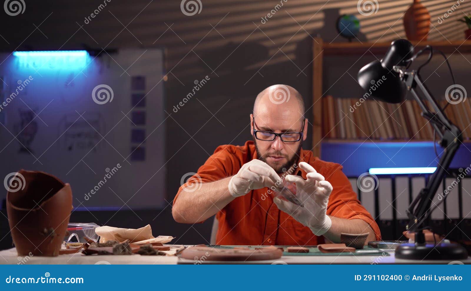 An Archaeologist Working in an Office at Night Puts an Ancient Artifact ...