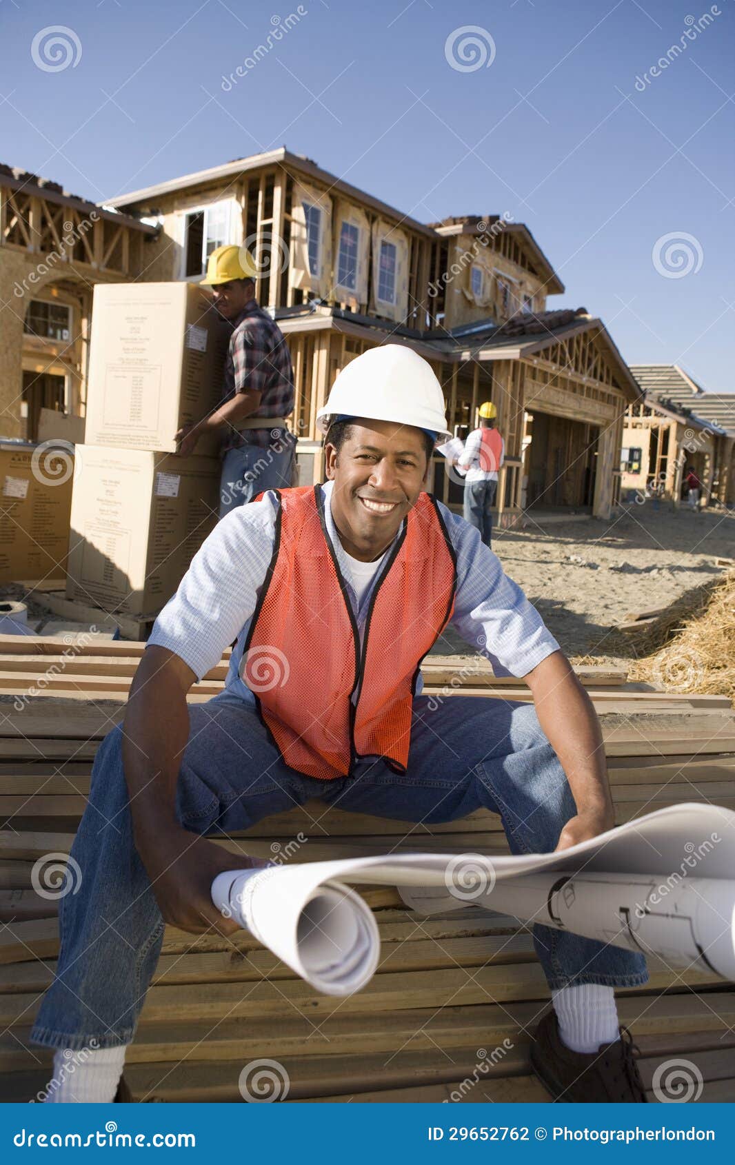 Architect with Blueprint and Workers Working in Background Stock Photo ...