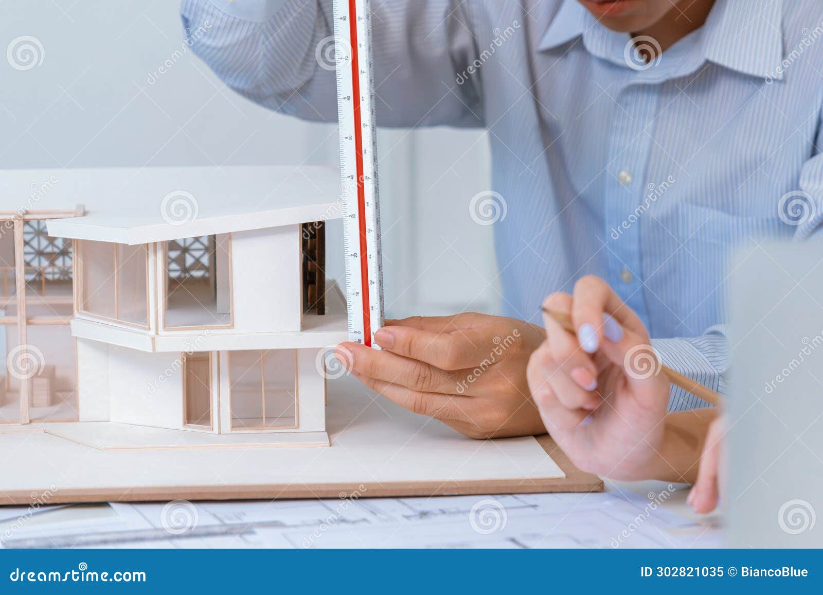 Architect Measures House Model Length while Colleague Using Laptop ...