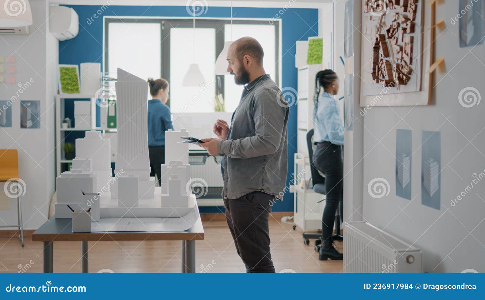 Architect Using Digital Tablet And Building Model To Design Blueprints Plans For Construction