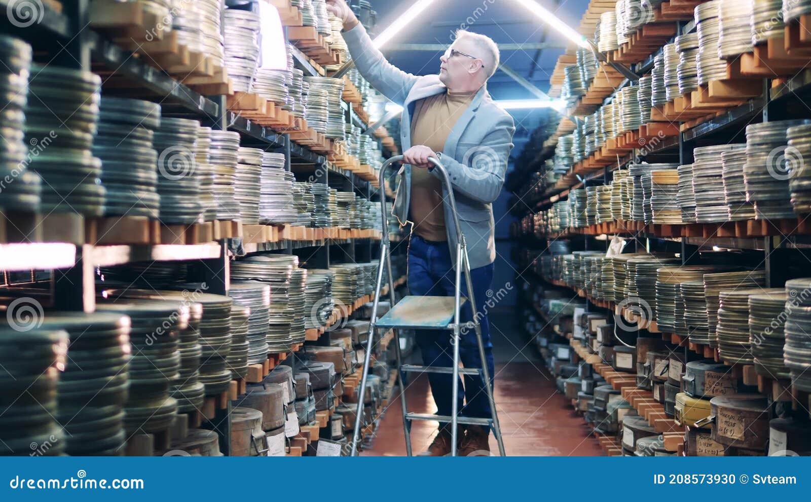 Archive Worker is Using a Ladder To Get a Case with Film Reel Stock ...