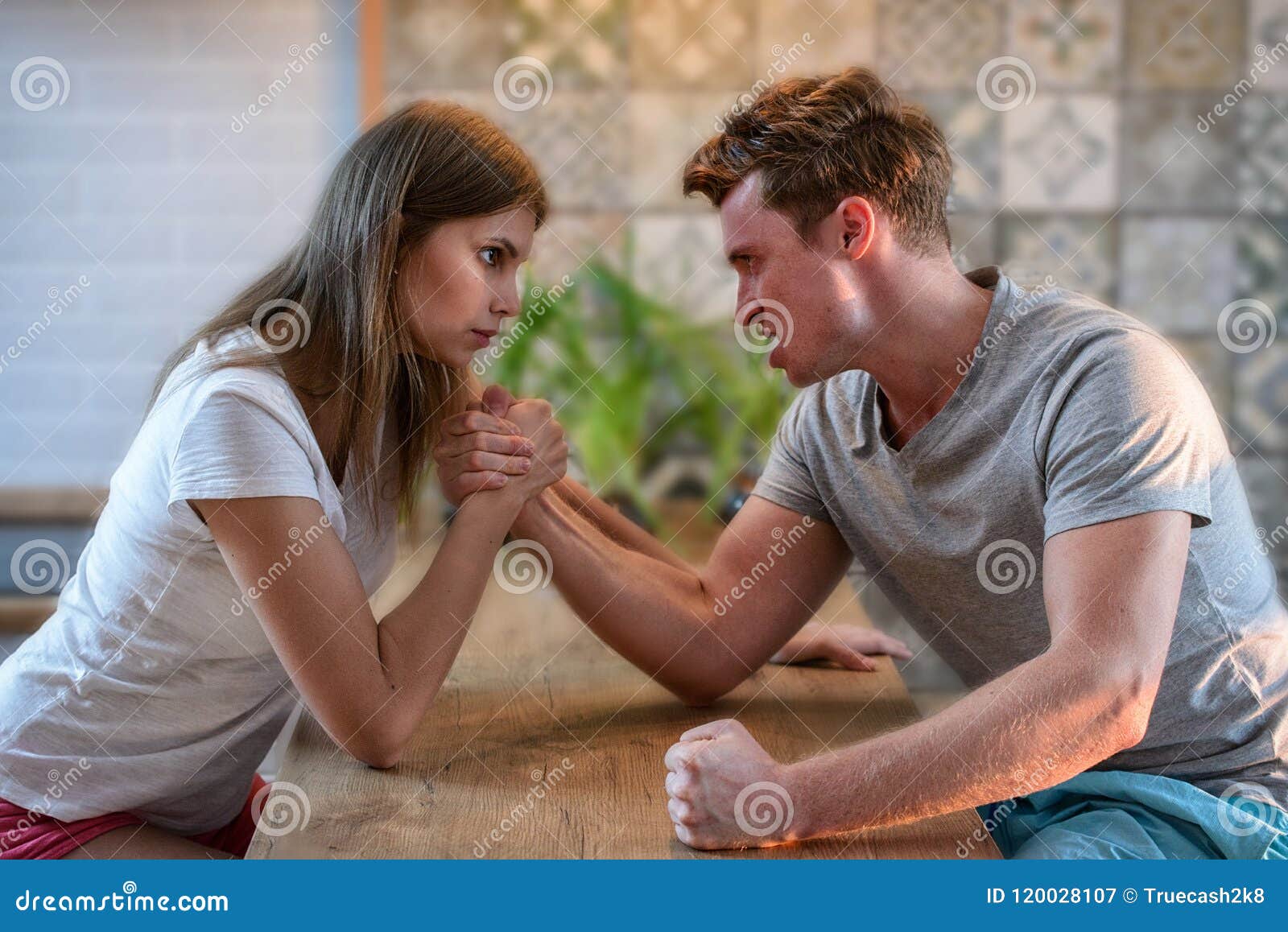 Arm Wrestling Challenge Between Young Man And Woman Couple Household
