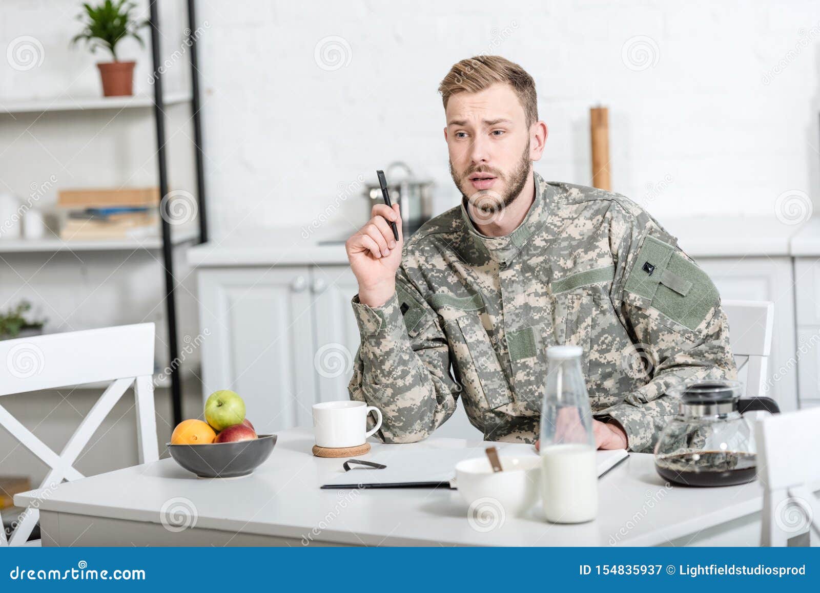 Army Soldier Sitting at Kitchen Table with Pen while Stock Image ...