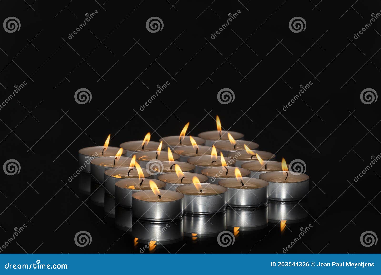 Arrangement of Lit Tea Light Candles on a Reflective Surface on a Dark ...