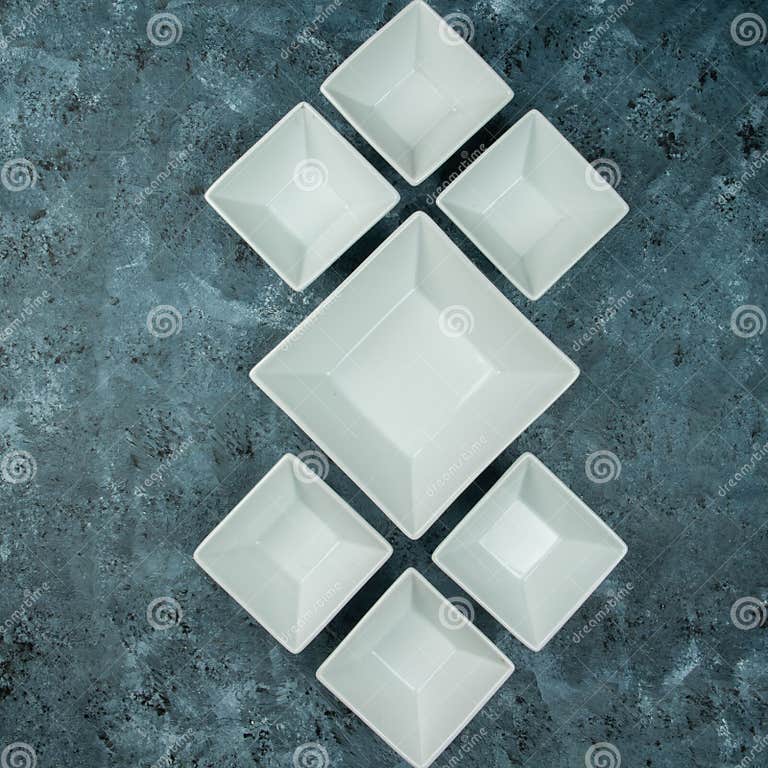 Array of Square Ceramic Plates Arranged in a Neat Pattern on a Blue ...
