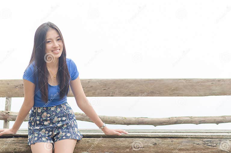 Asia Young Shy Women Sitting And Smile On Wood Long Chair Stock Image