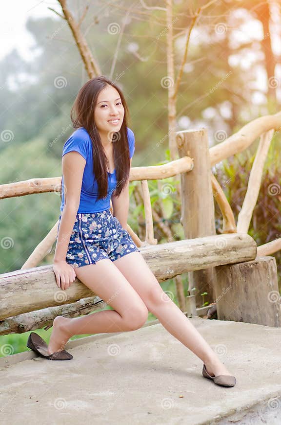 Asia Young Shy Women Sitting And Smile On Wood Long Chair Stock Image