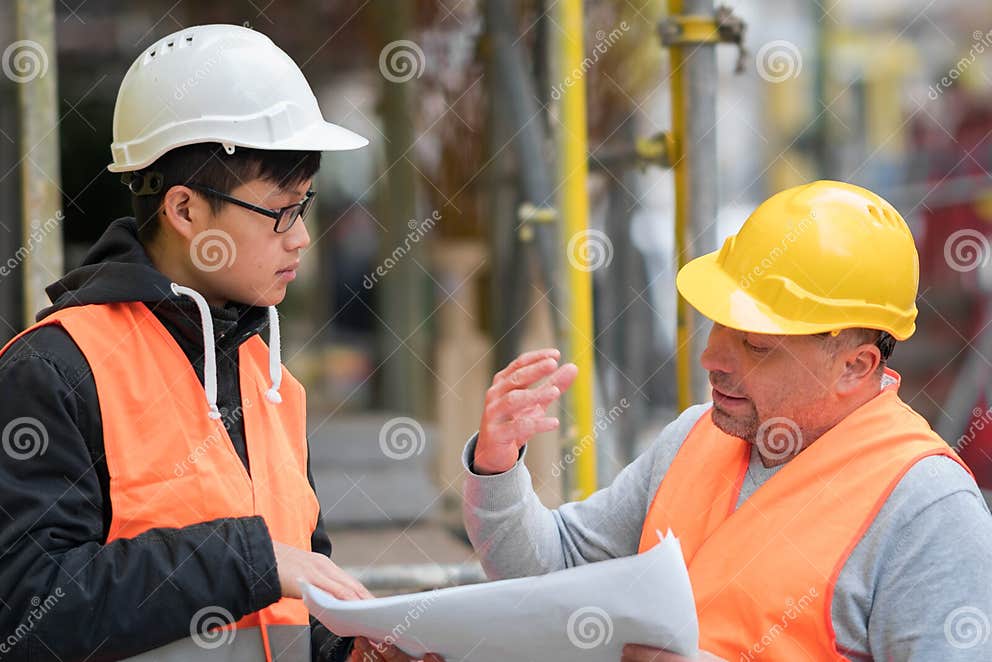 Asian Apprentice Engineer at Work on Construction Site with the Senior ...