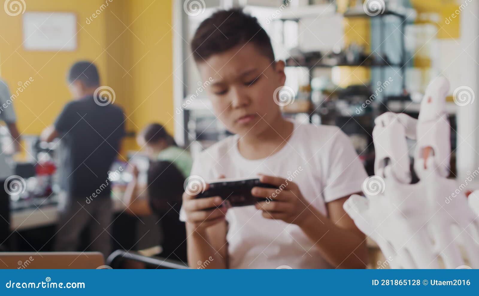 Asian Boy Programming the Robot Hand. Group of Schoolchildren ...
