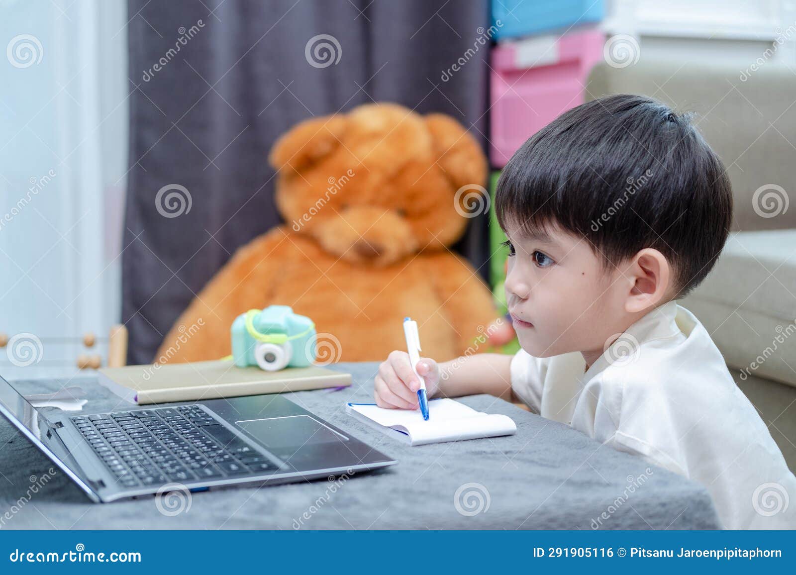 Asian Boy Taking Notes on Paper while Studying Online on Laptop Stock ...