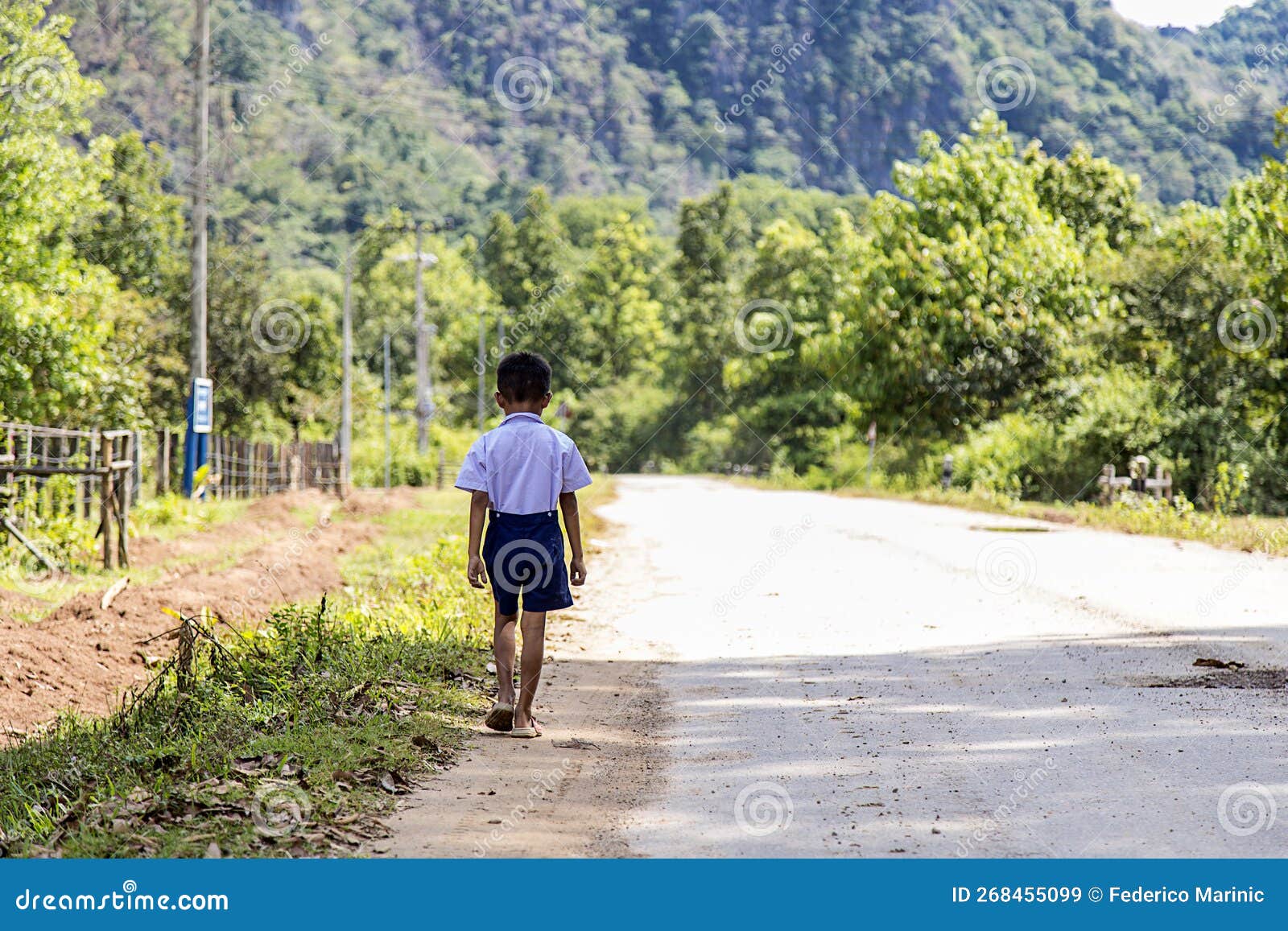 Asian Boy Walking on the Side of the Road with the Mountains and Many ...