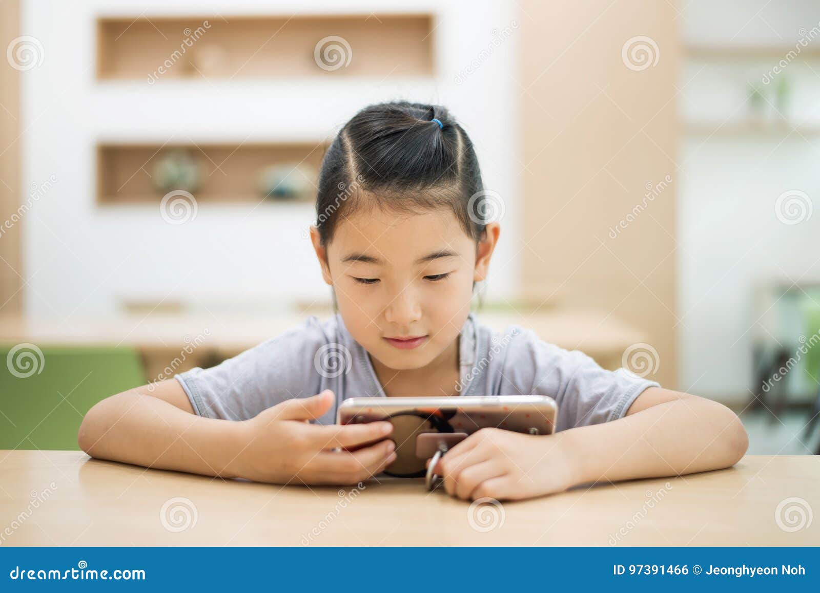Asian Child Looking at Smartphone at Library Desk. Stock Photo - Image ...