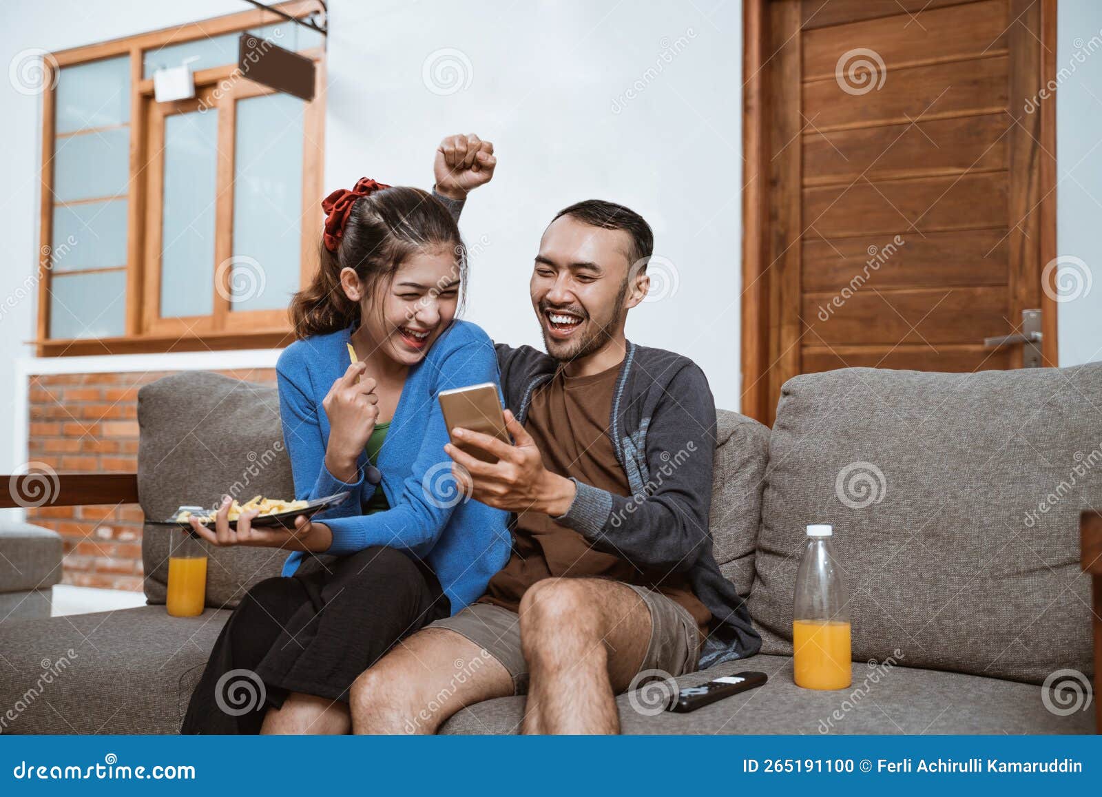 Asian Couple Laughing While Looking At Cell Phone Screen Together Stock