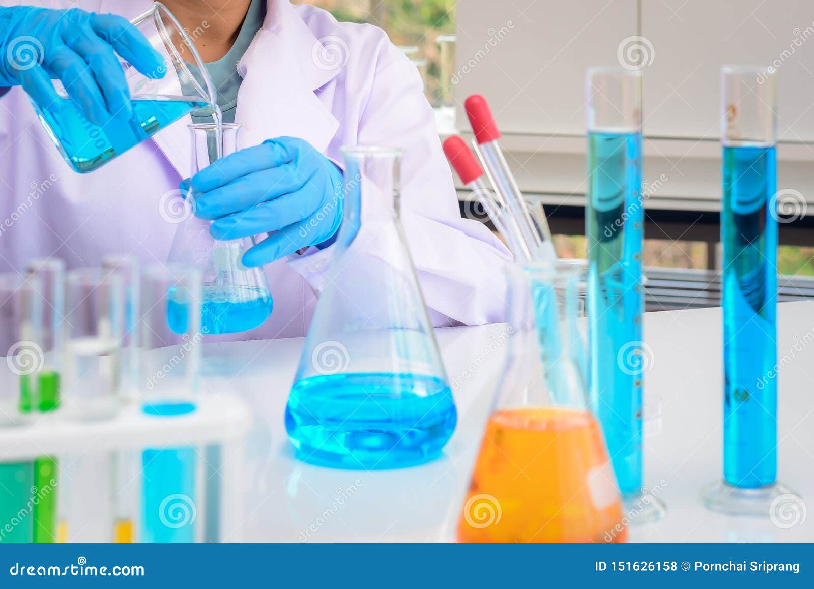 Asian Female Scientists are Pouring a Blue Solution from the Beaker ...