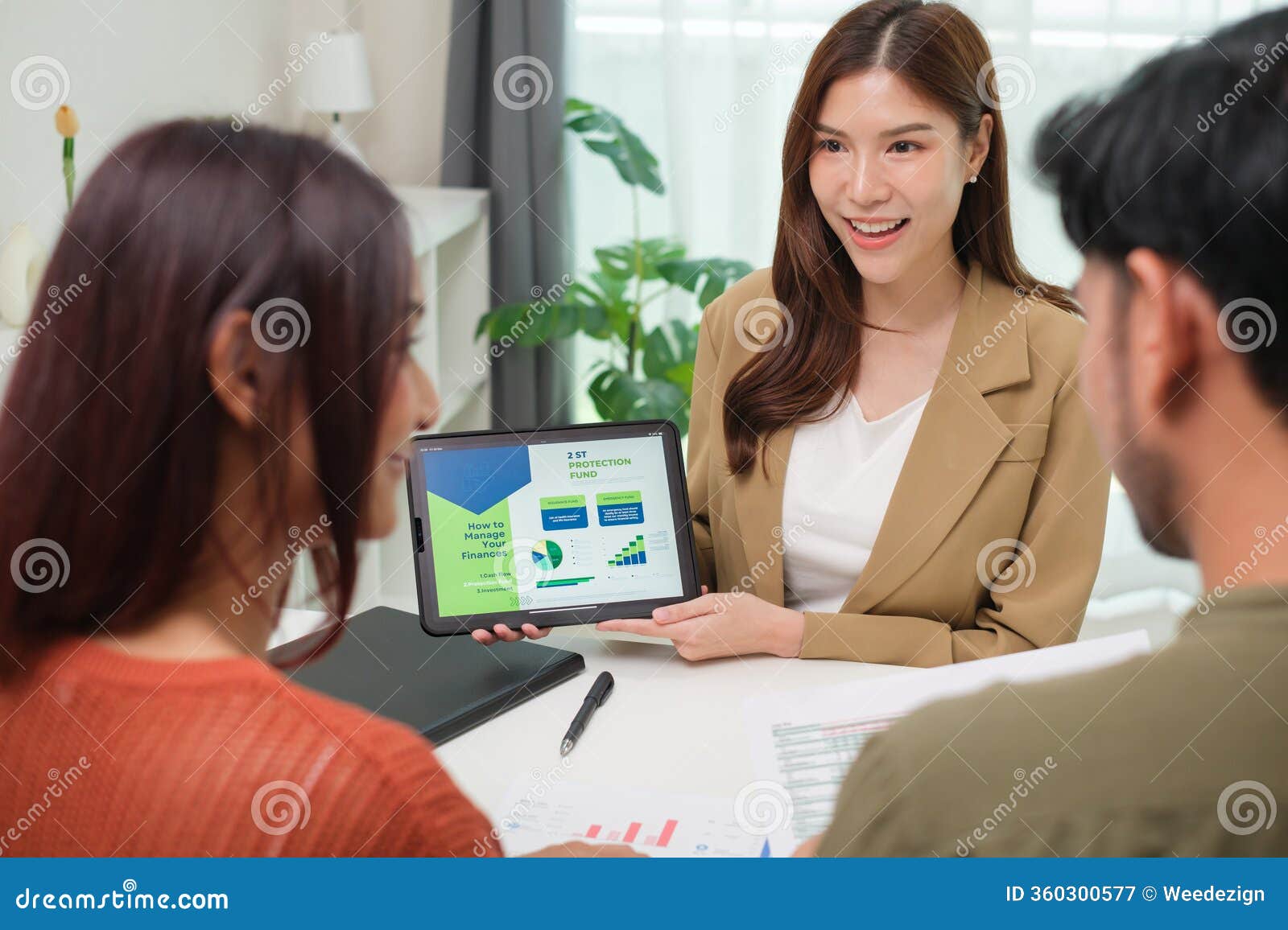Asian Financial Advisor Presenting Charts and Data on a Tablet during ...