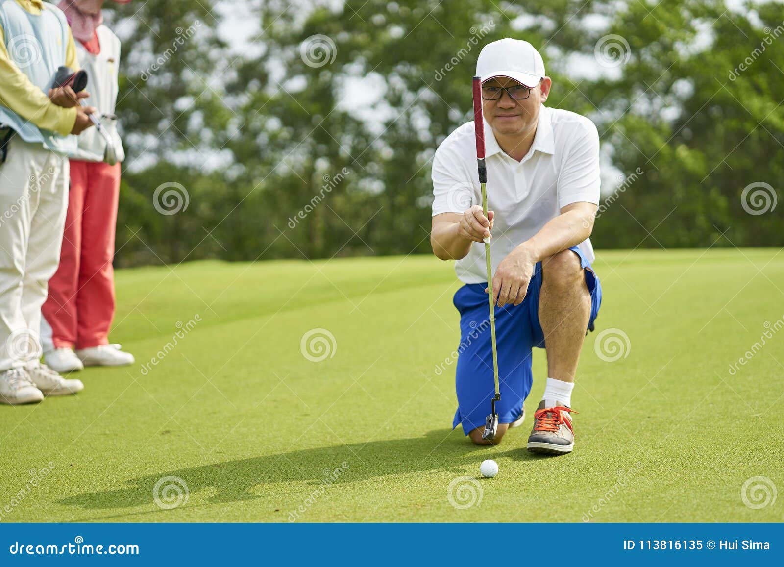Asian Golfer Crouching in Golf Course Aiming and Preparing for Putting ...