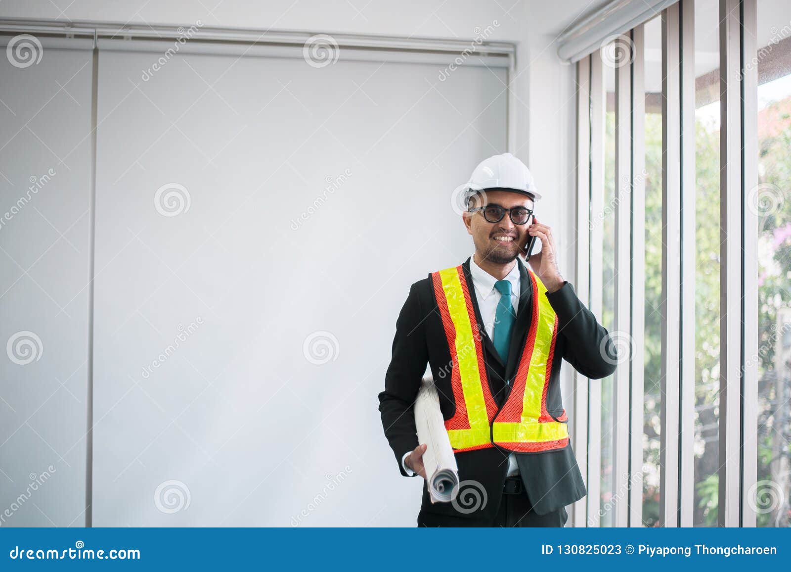 Asian Man Engineers Using Mobile Phone and Holding Blueprint in Office ...