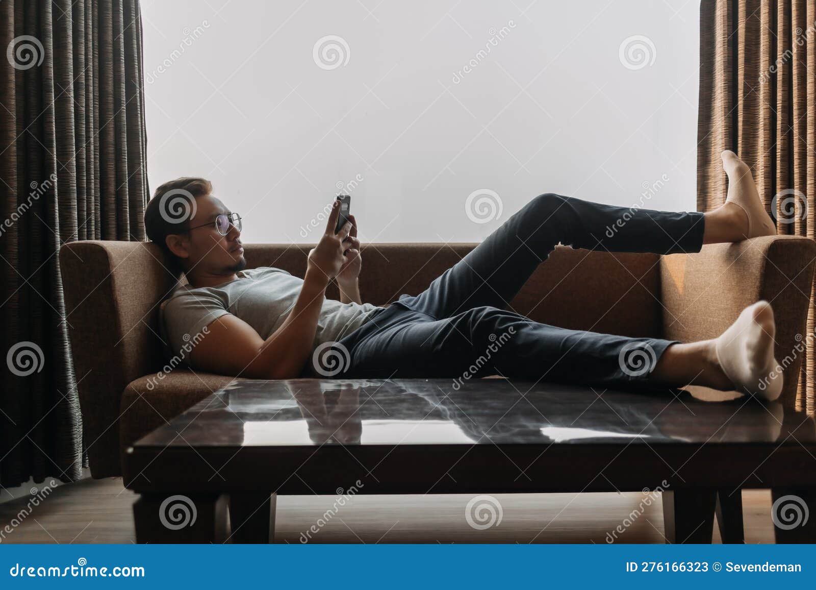 Man Lies on Sofa Using Phone with His Feet on the Table. Concept of ...
