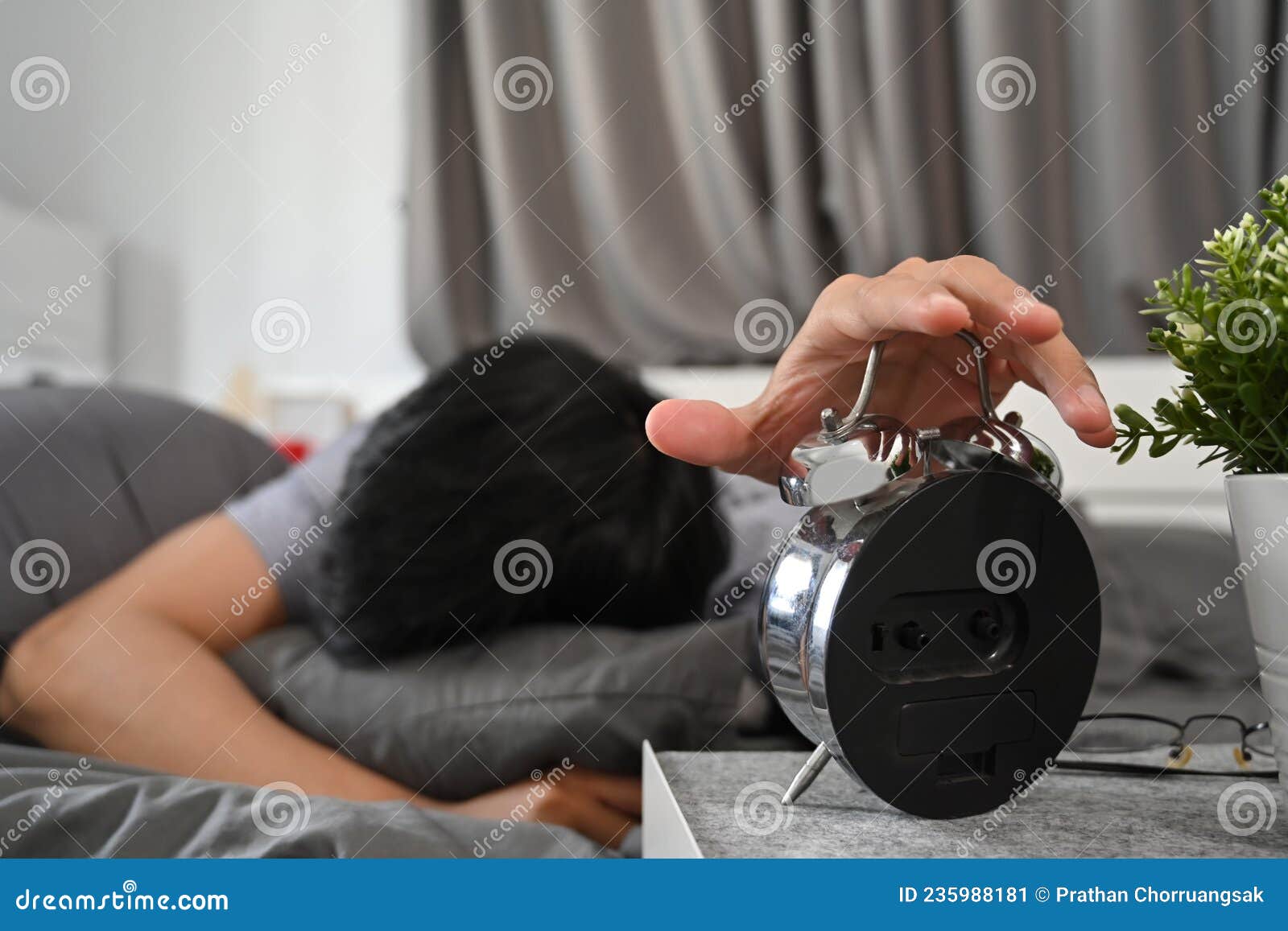 Man Lying In Bed And Turning Off An Alarm Clock In The Morning Stock