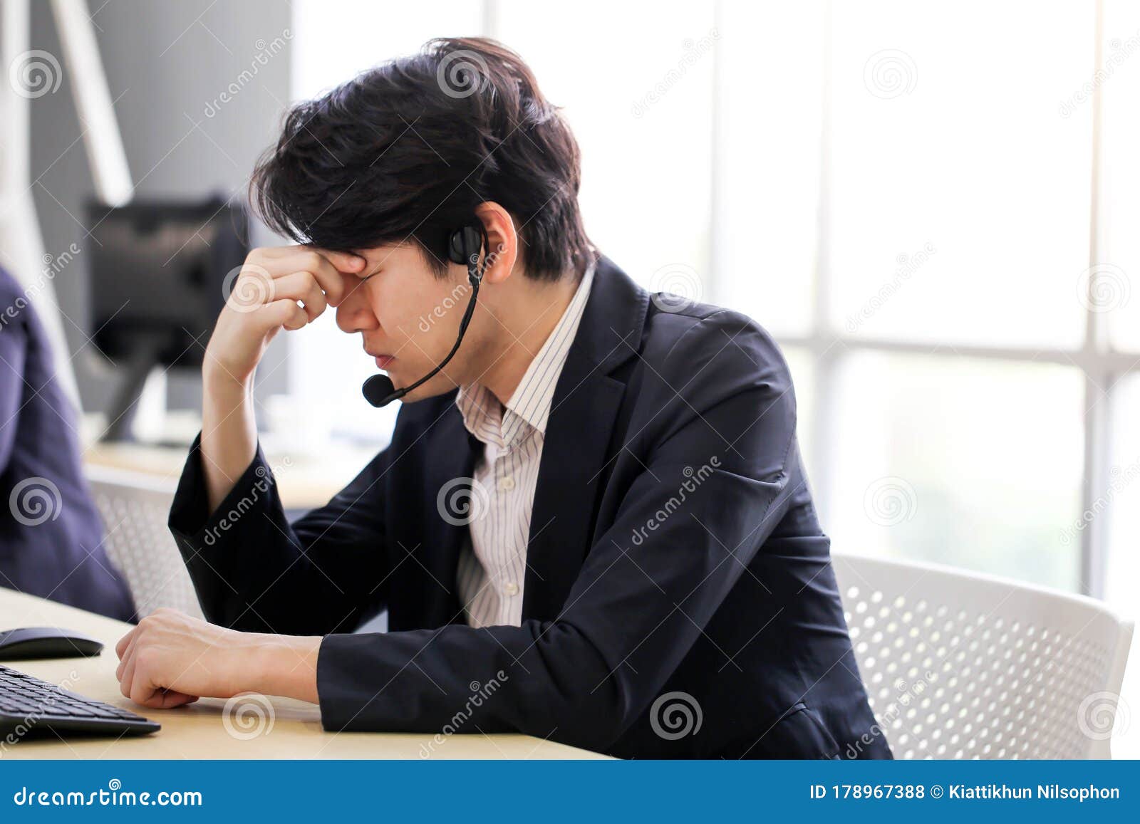 Asian Man Serious Call Center Operator in Wireless Headset Talking with ...