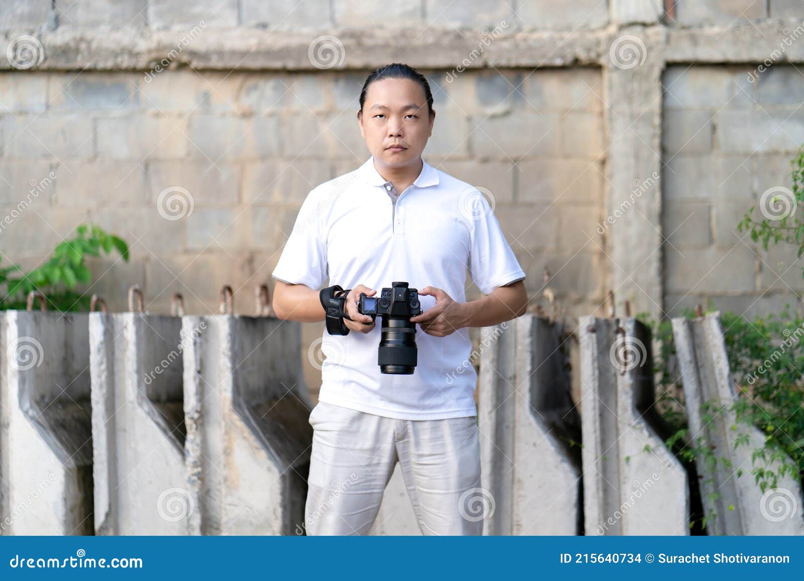 Asian Man Serious Looks at the Camera while Holds Th Mirrorless Camera ...