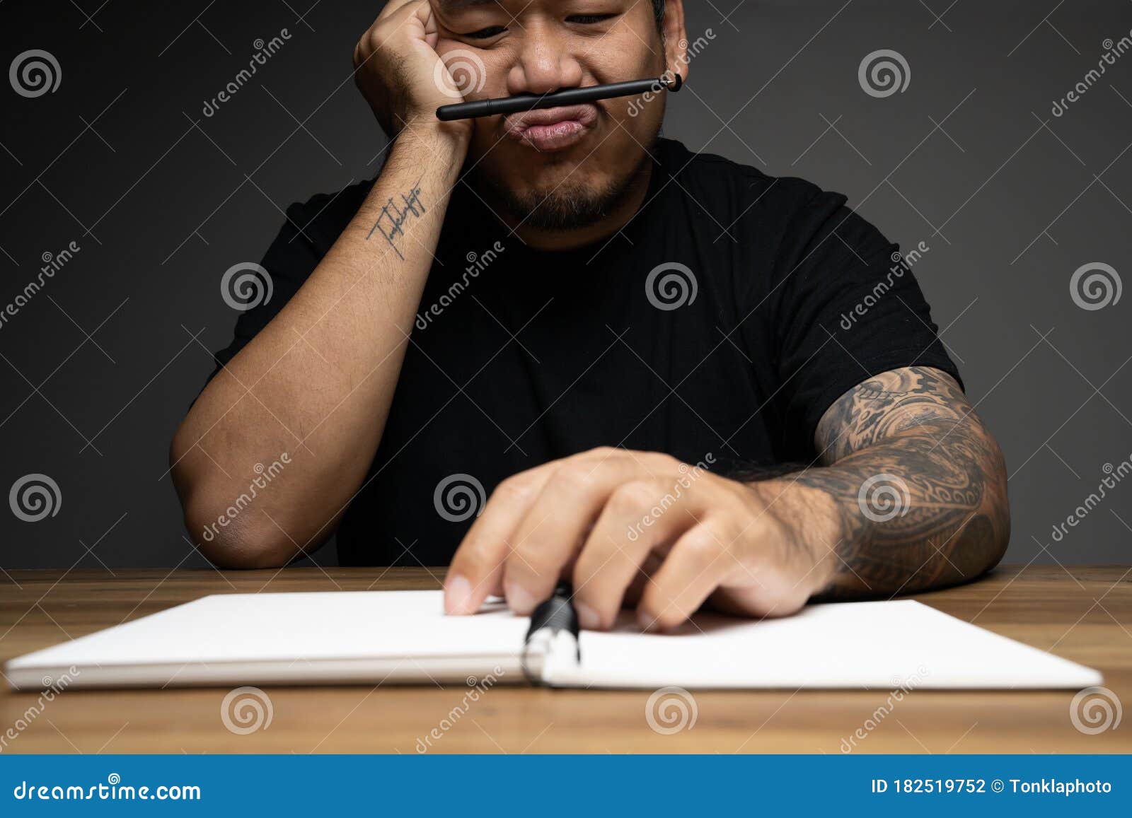 Asian Man Writing on a Note Book with Thinking Face on Wooden Table ...