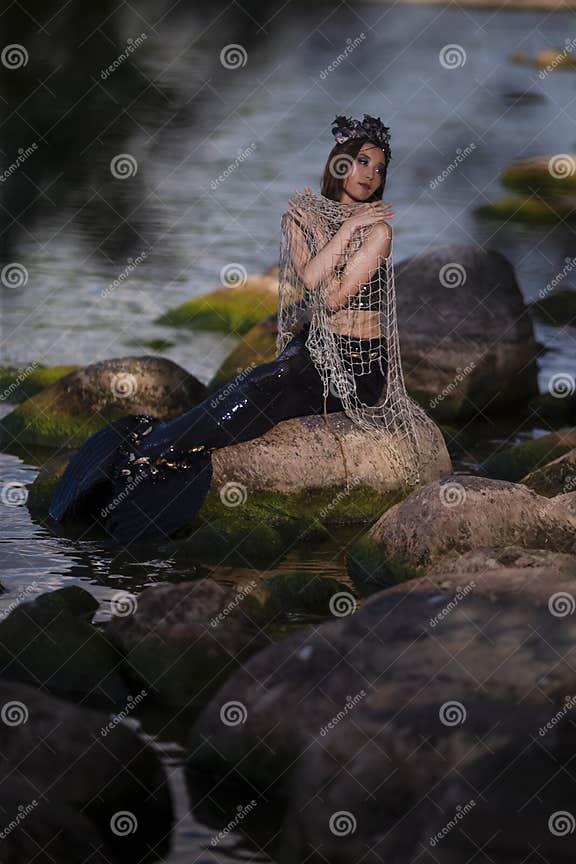 Asian Mermaid Embracing With Net At Sea Shore On Rocks While Wearing