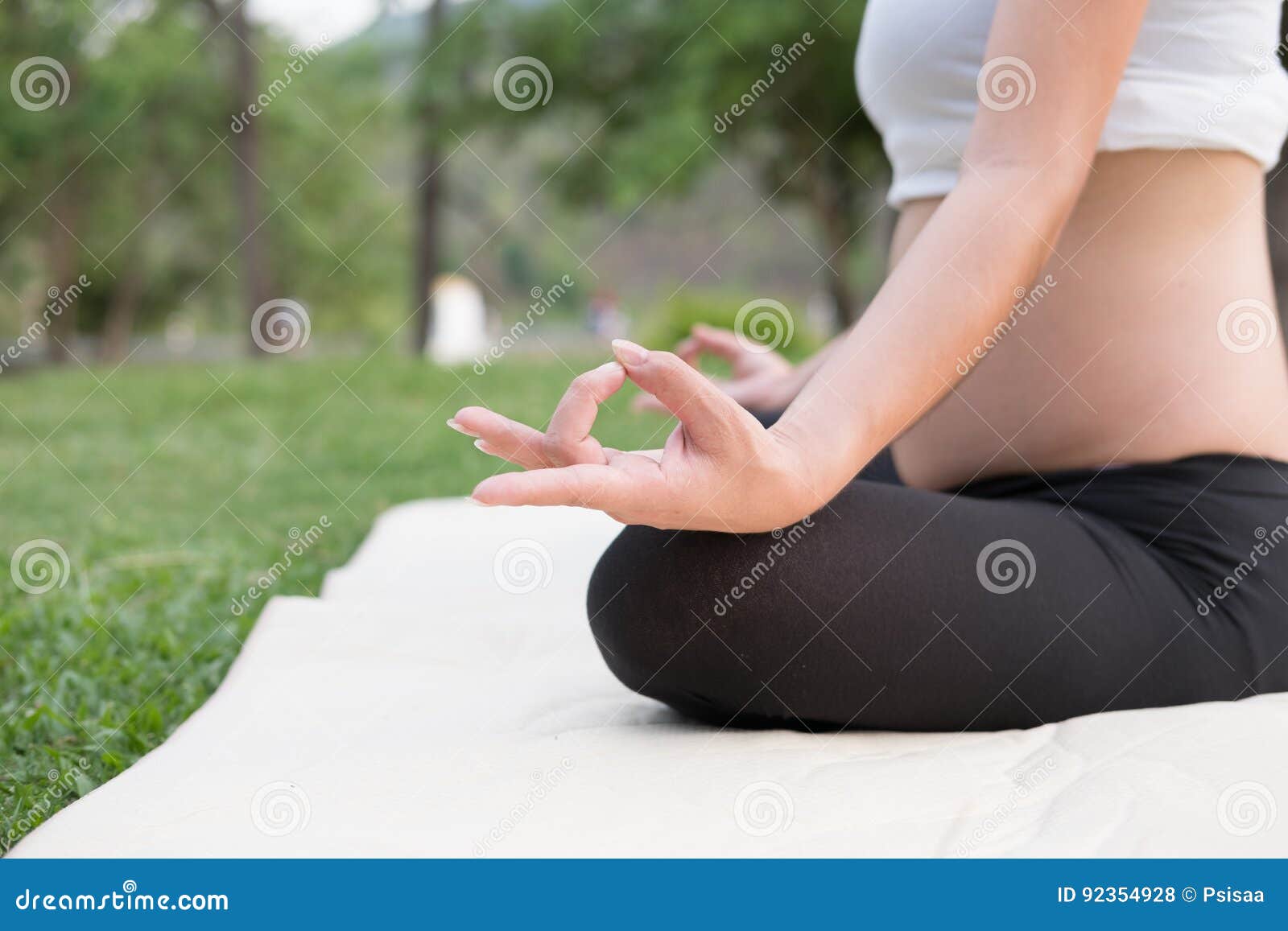 Asian Pregnant Woman Practicing Yoga While Sitting In Lotus Position On