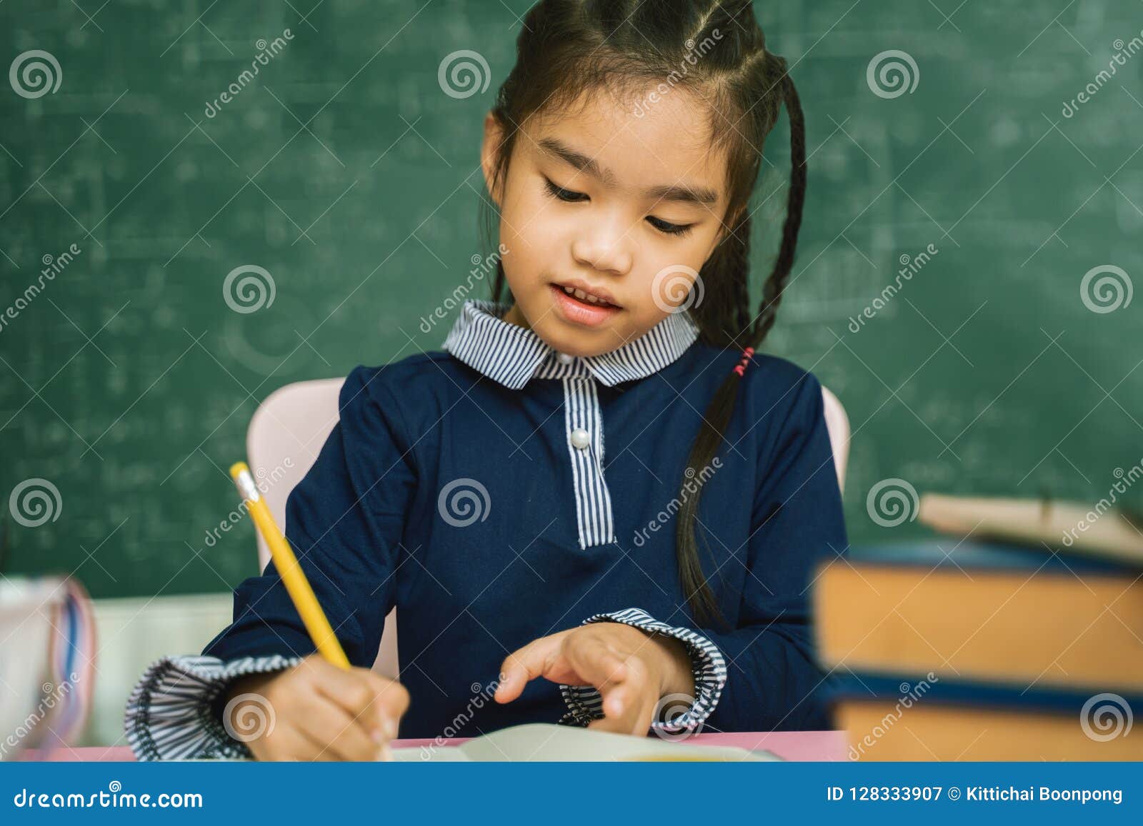 Asian Primary School Student Studying Homework in Classroom. Stock ...