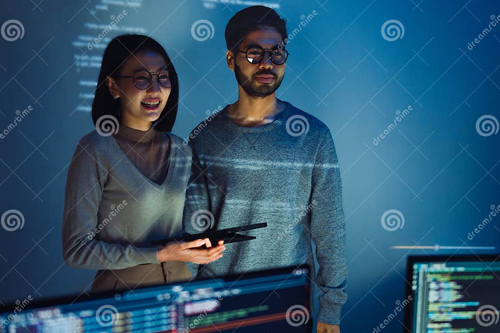 Asian Two Software Developers Engaged in Collaborative Coding Session, with Code Projected Onto ...