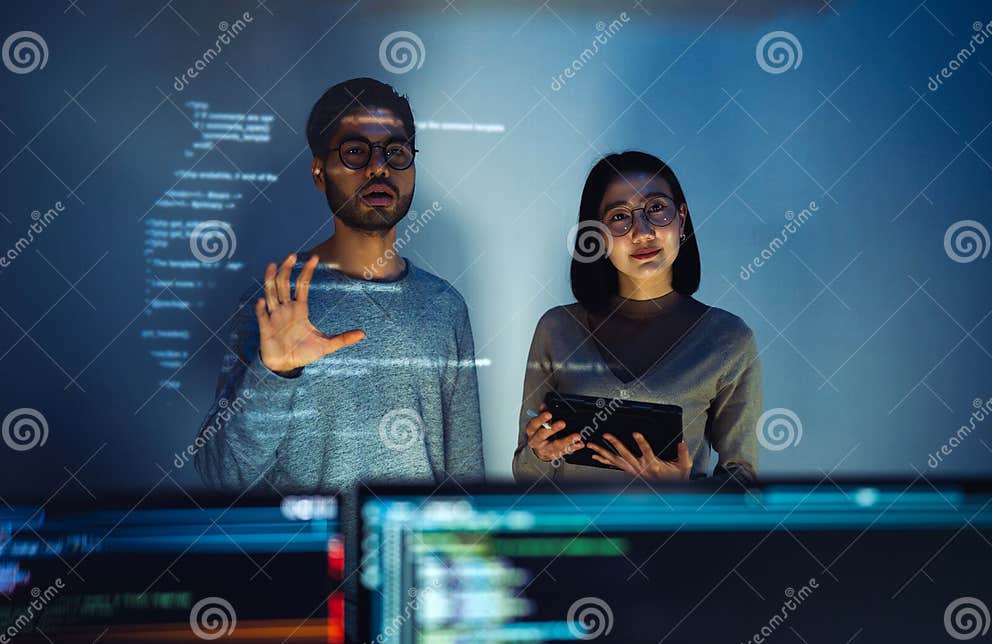 Asian Two Software Developers Engaged in Collaborative Coding Session, with Code Projected Onto ...