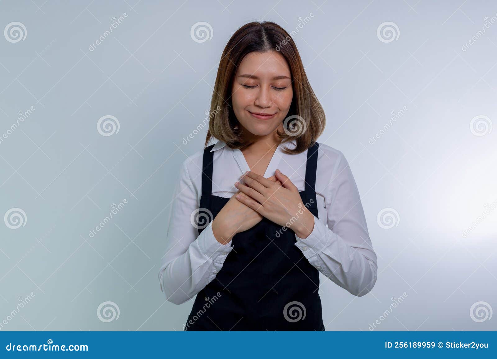 Asian Woman Holding Hands On Heart Looking Pleased And Happy Stock