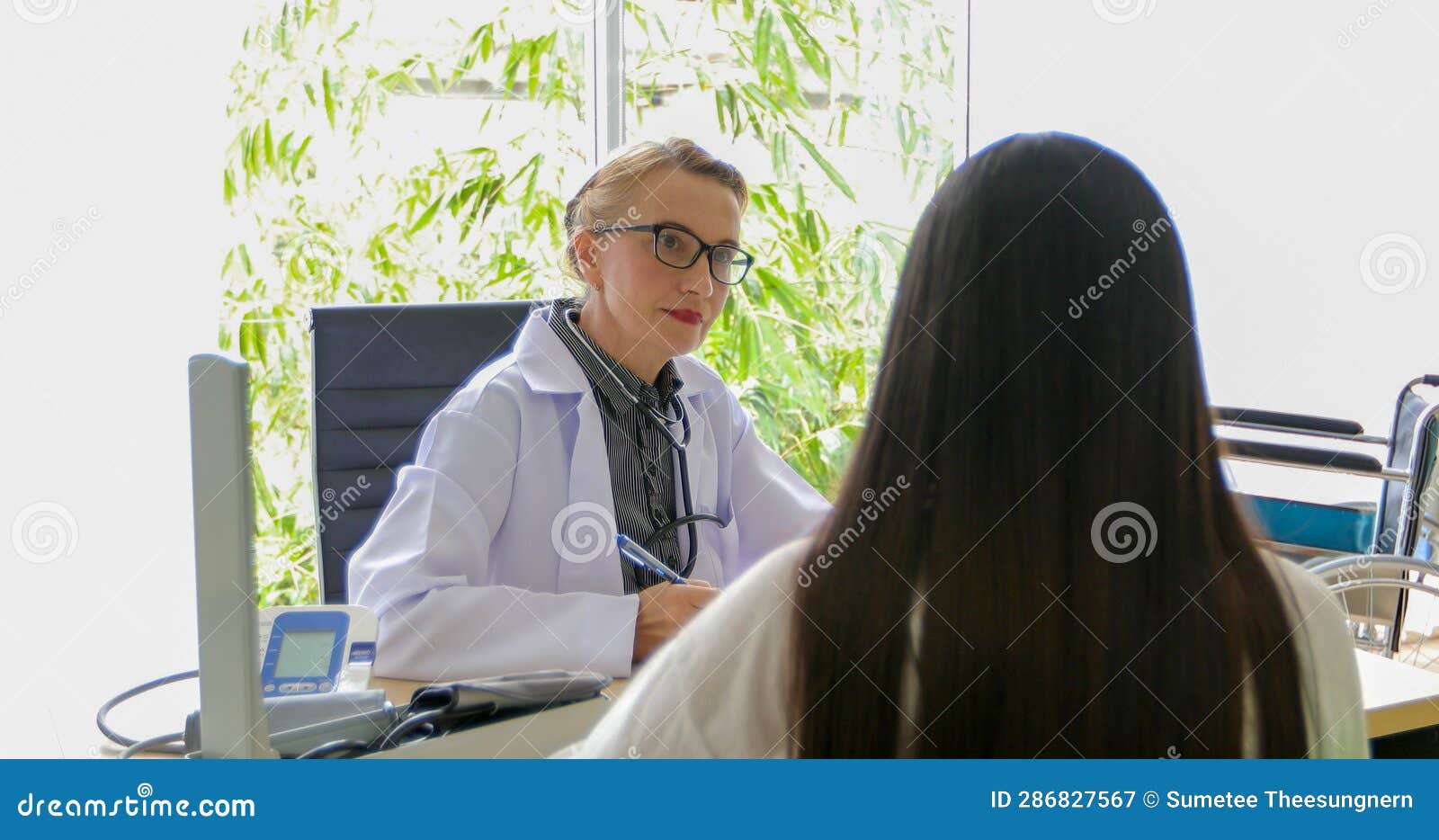 Asian Woman Patient Sitting With Doctor About Her Illness And Showing X