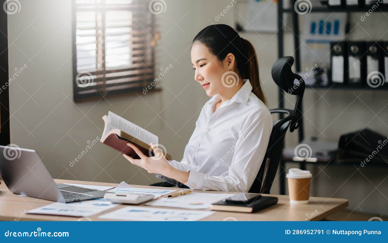 Asian Woman Reading Book While Sitting At In Cafe Or Home Office Stock