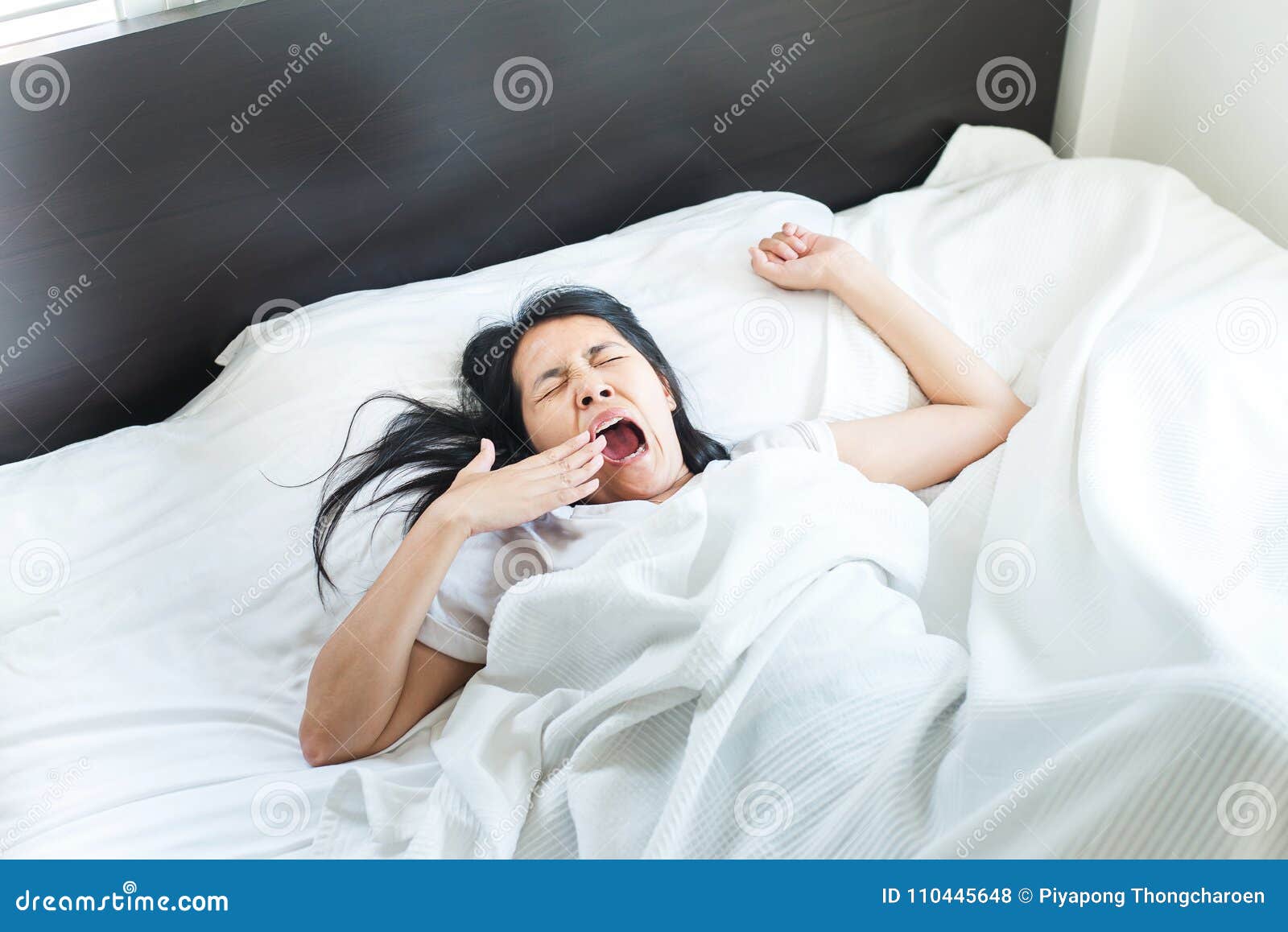 Asian Woman Stretching And Yawning Or Gape Feeling Lazy On Bed After