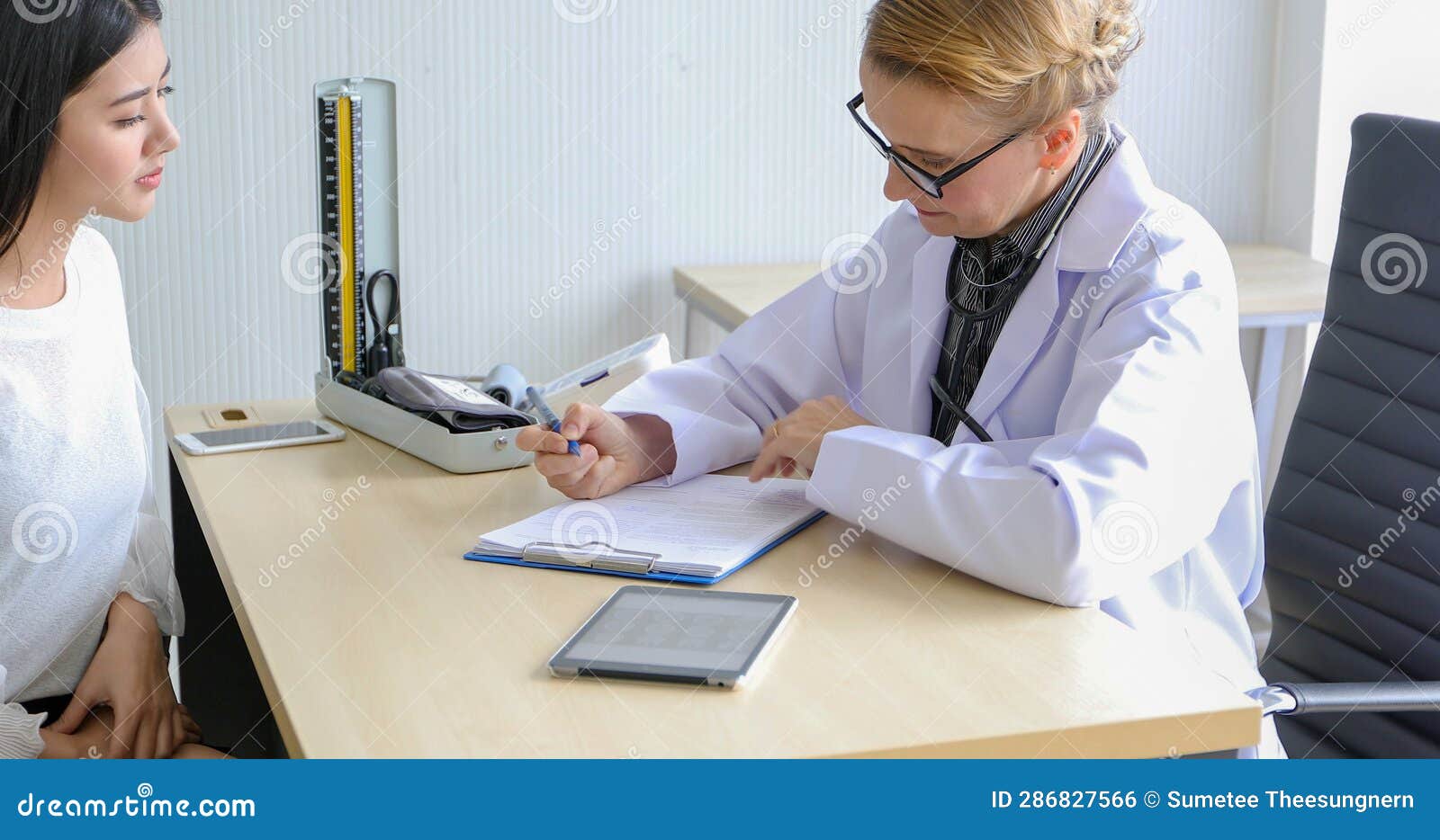 Asian Woman Patient Sitting With Doctor About Her Illness And Showing X