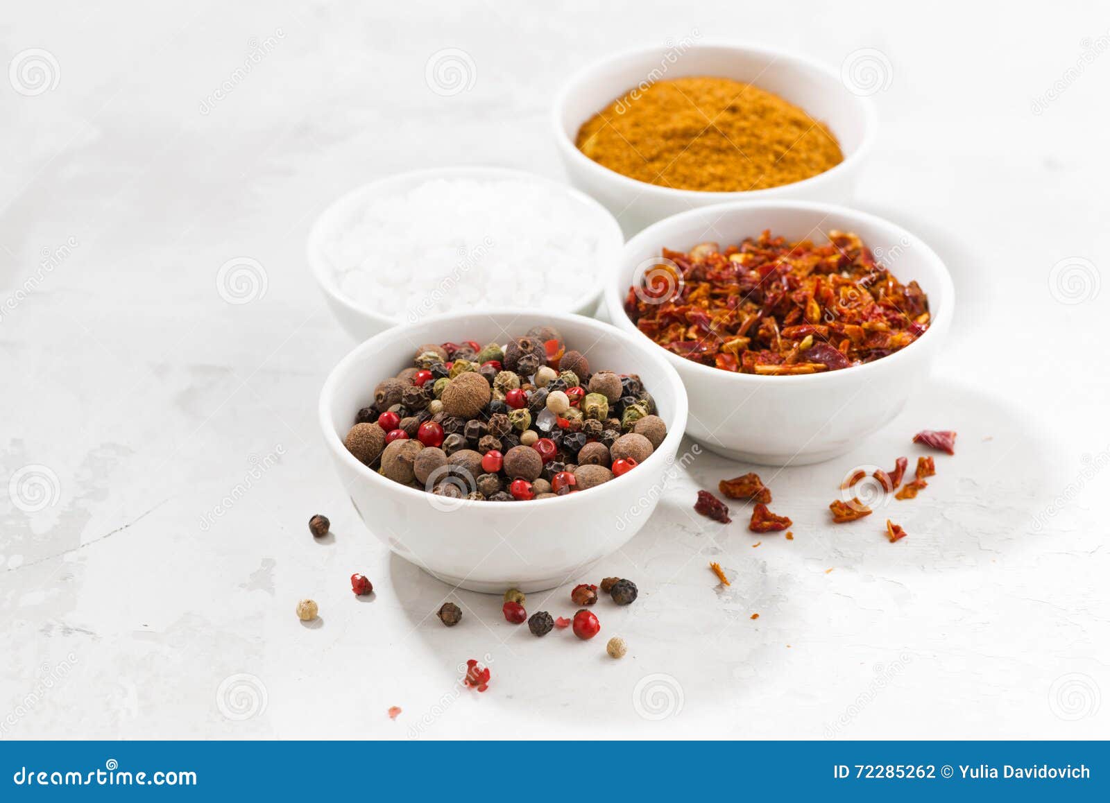 Assortment of Pepper, Salt and Spices in Bowls on White Table Stock ...