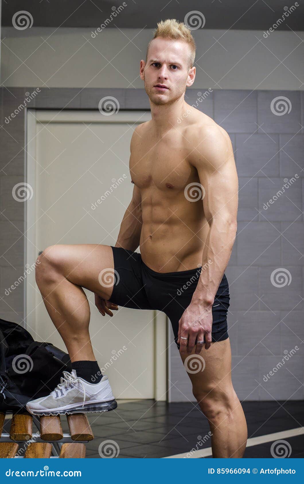 Athlete In Locker Room Tying Sneakers Shirtless Looking At Camera