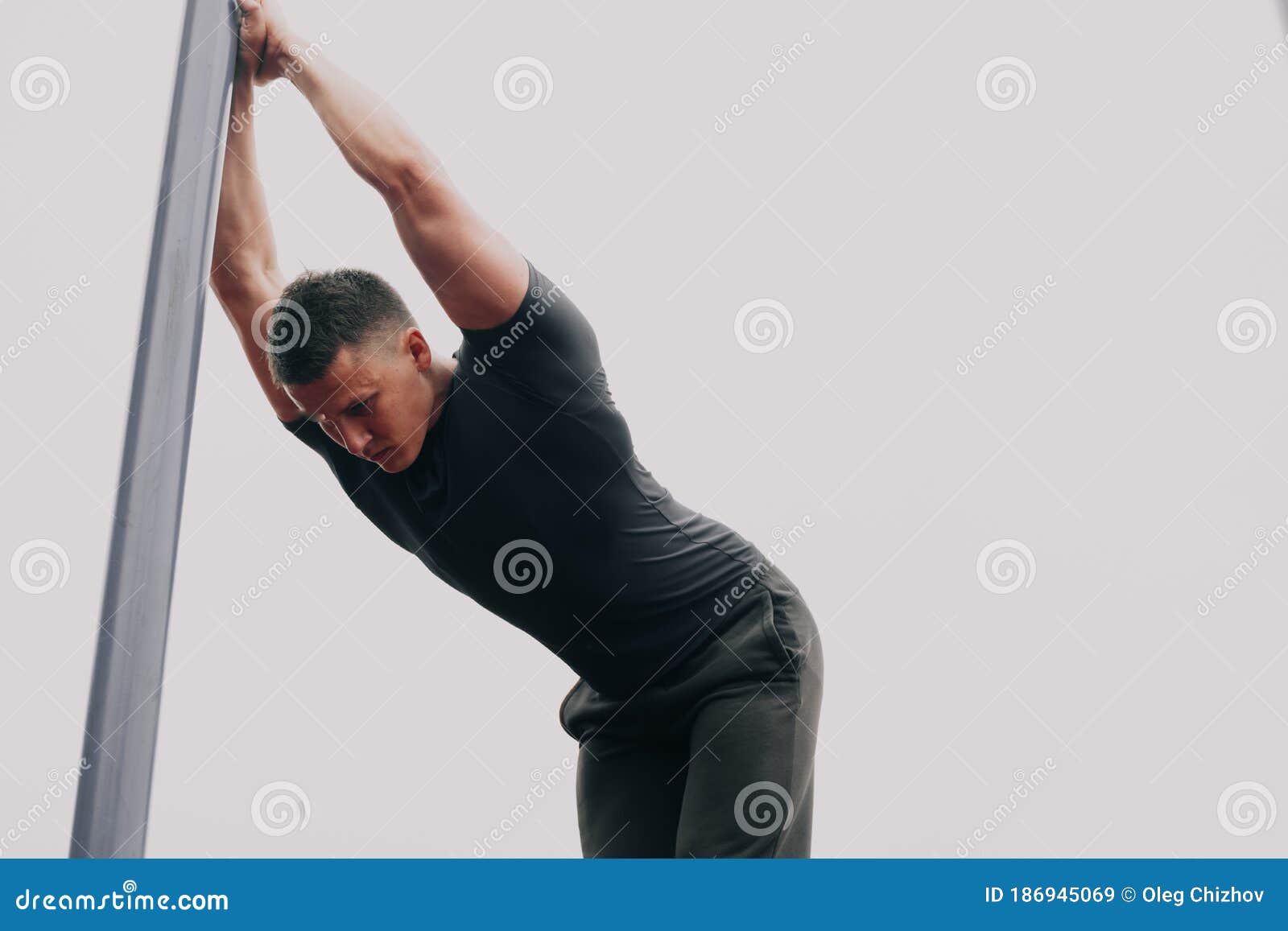 Athlete Young Guy Does a Warm Up on the Simulator. Stretching Back ...