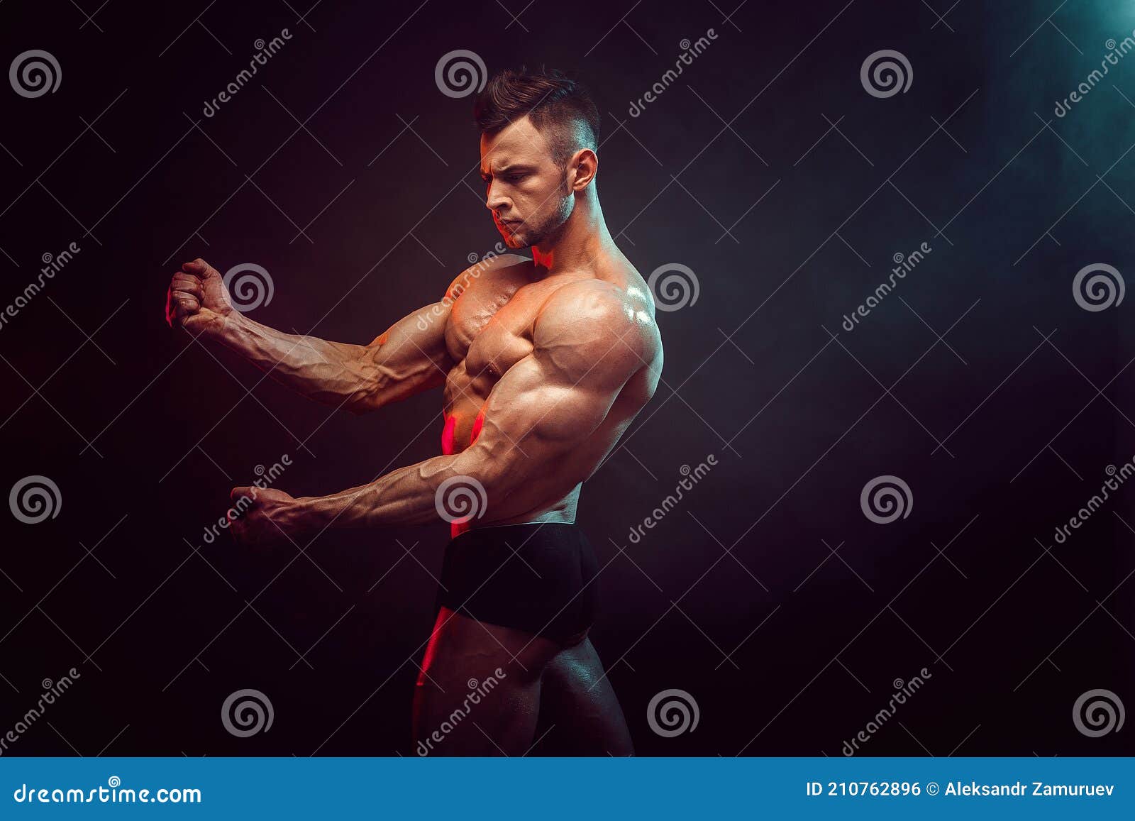 Athletic Man Flexing Muscles in Studio on Dark Background with Smoke ...
