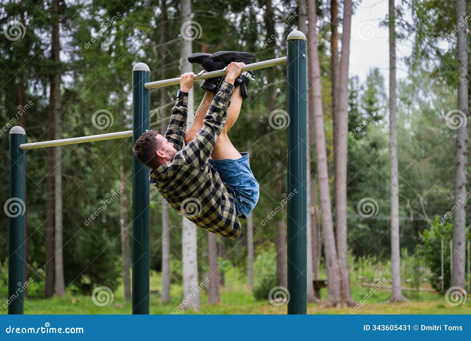 A Athletic Man in Gravity Boots Hangs on a Horizontal Bar Outdoors on a ...