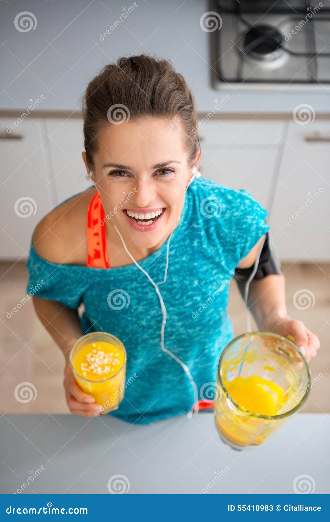 Athletic Smiling Woman Holding Freshly Made Smoothie In Kitchen Stock