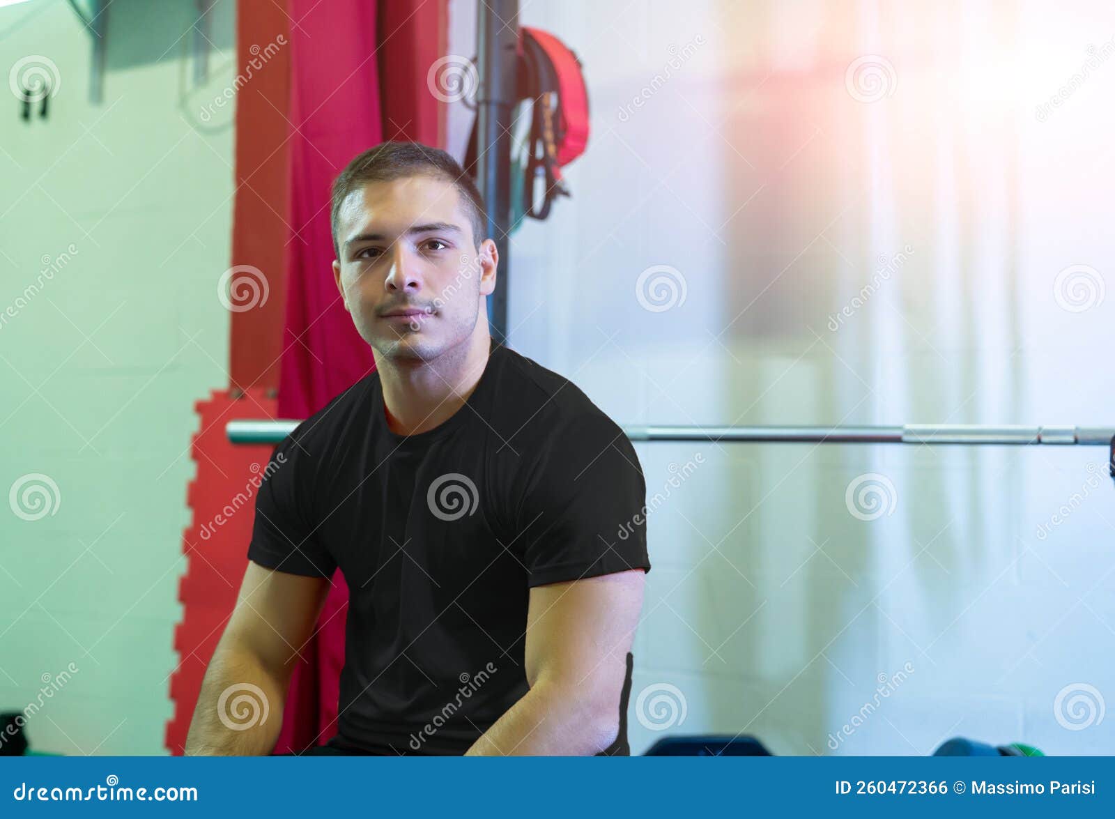 Athletic Young Man Poses Seated on the Bench Press Looking at the ...