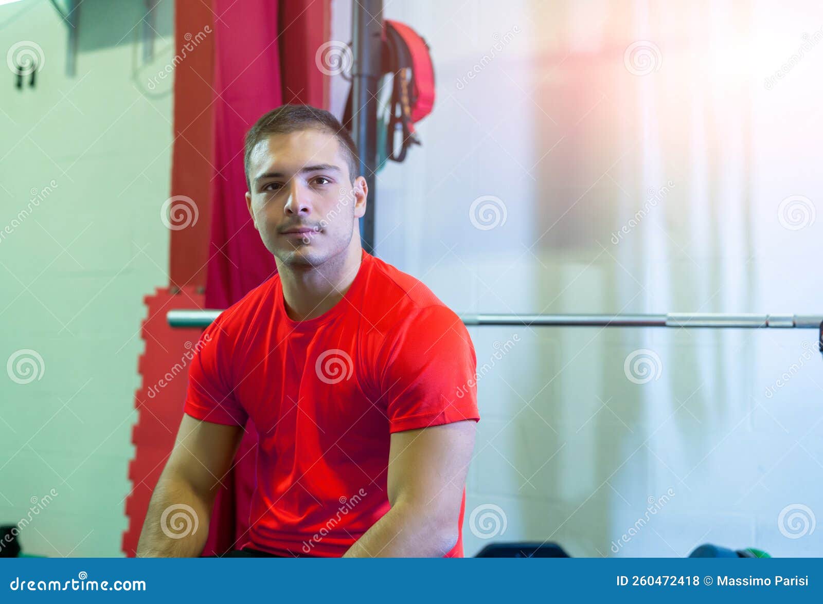 Athletic Young Man Poses Seated on the Bench Press Looking at the ...