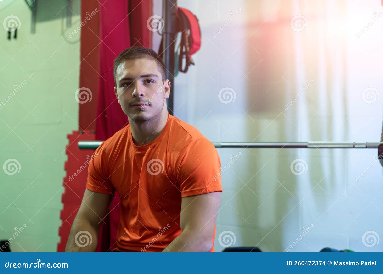 Athletic Young Man Poses Seated on the Bench Press Looking at the ...