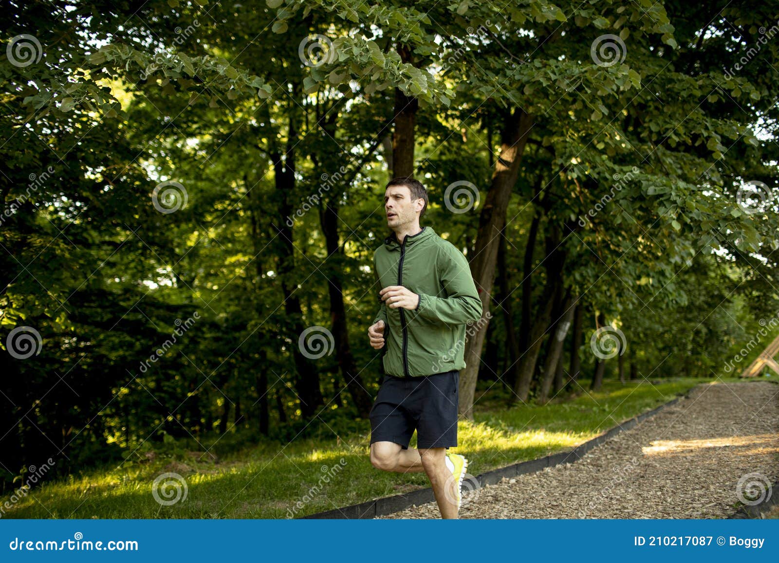 Athletic Young Man Running while Doing Workout in Sunny Green Park ...
