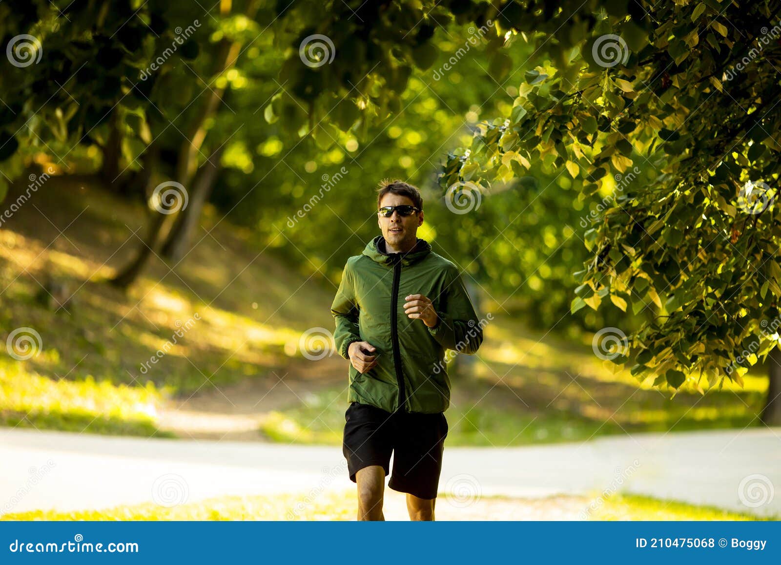 Athletic Young Man Running while Doing Workout in Sunny Green Park ...